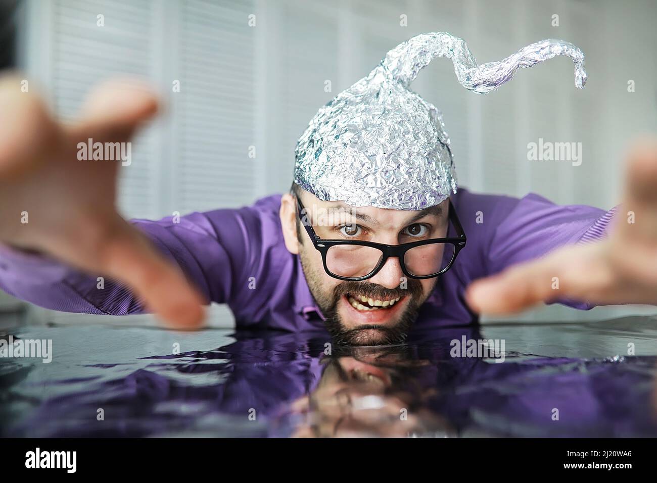 Bearded funny man in cap of aluminum foil. Concept art phobias ...