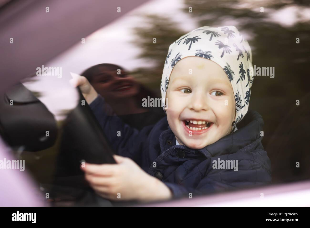 Little boy playing with a steering wheel in a car. Hands of a small ...
