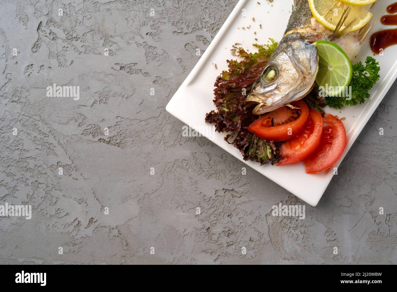Fresh sea fish with lemon on plate Stock Photo - Alamy