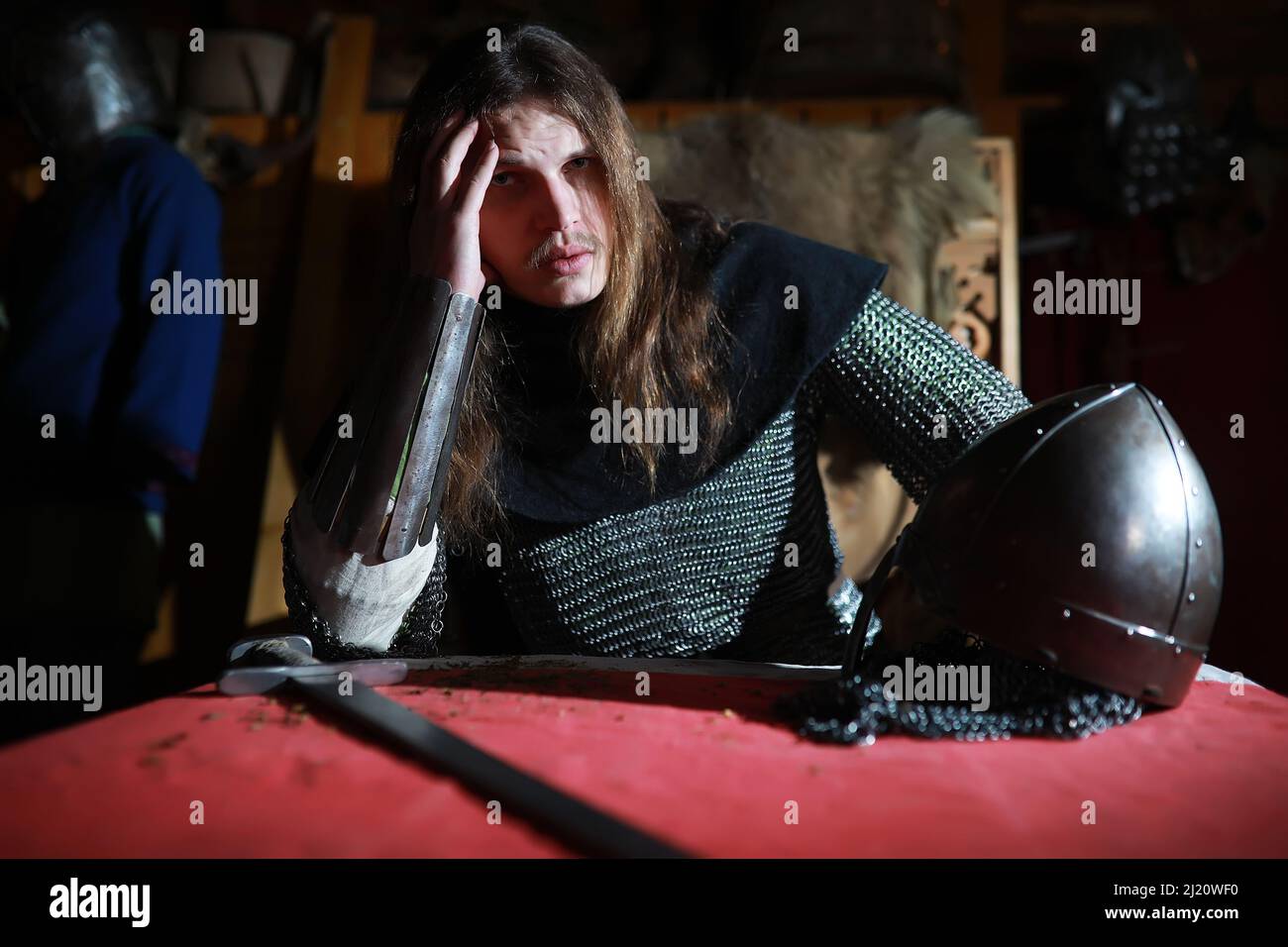 A mighty hero with long hair in chain mail armor in an ancient hall. Medieval warrior in knight ...