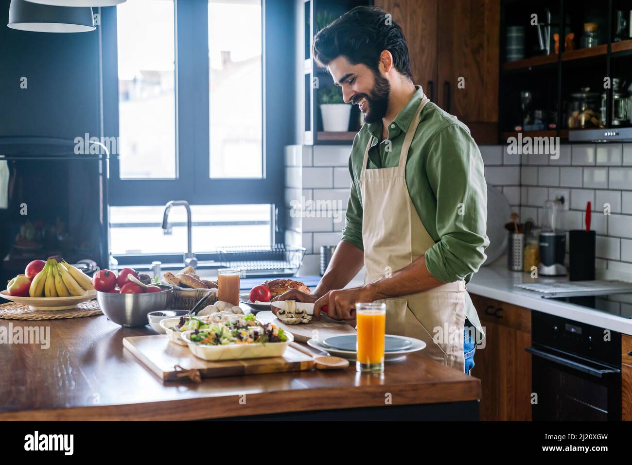Portrait of handsome smiling man cutting vegetables at kitchen Stock ...