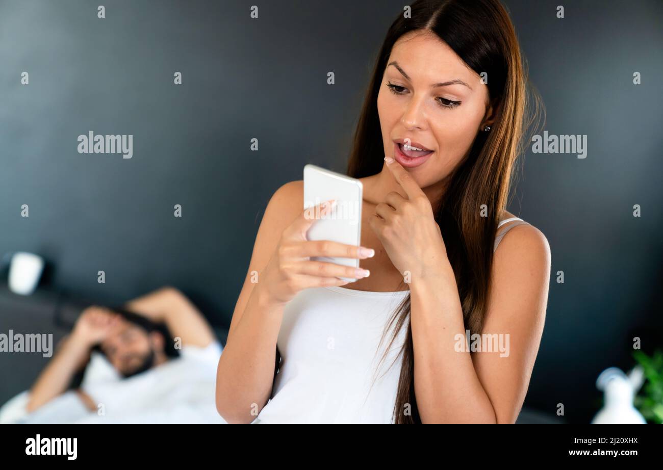 Woman talking privately on cellphone while her husband sleeping on bed ...