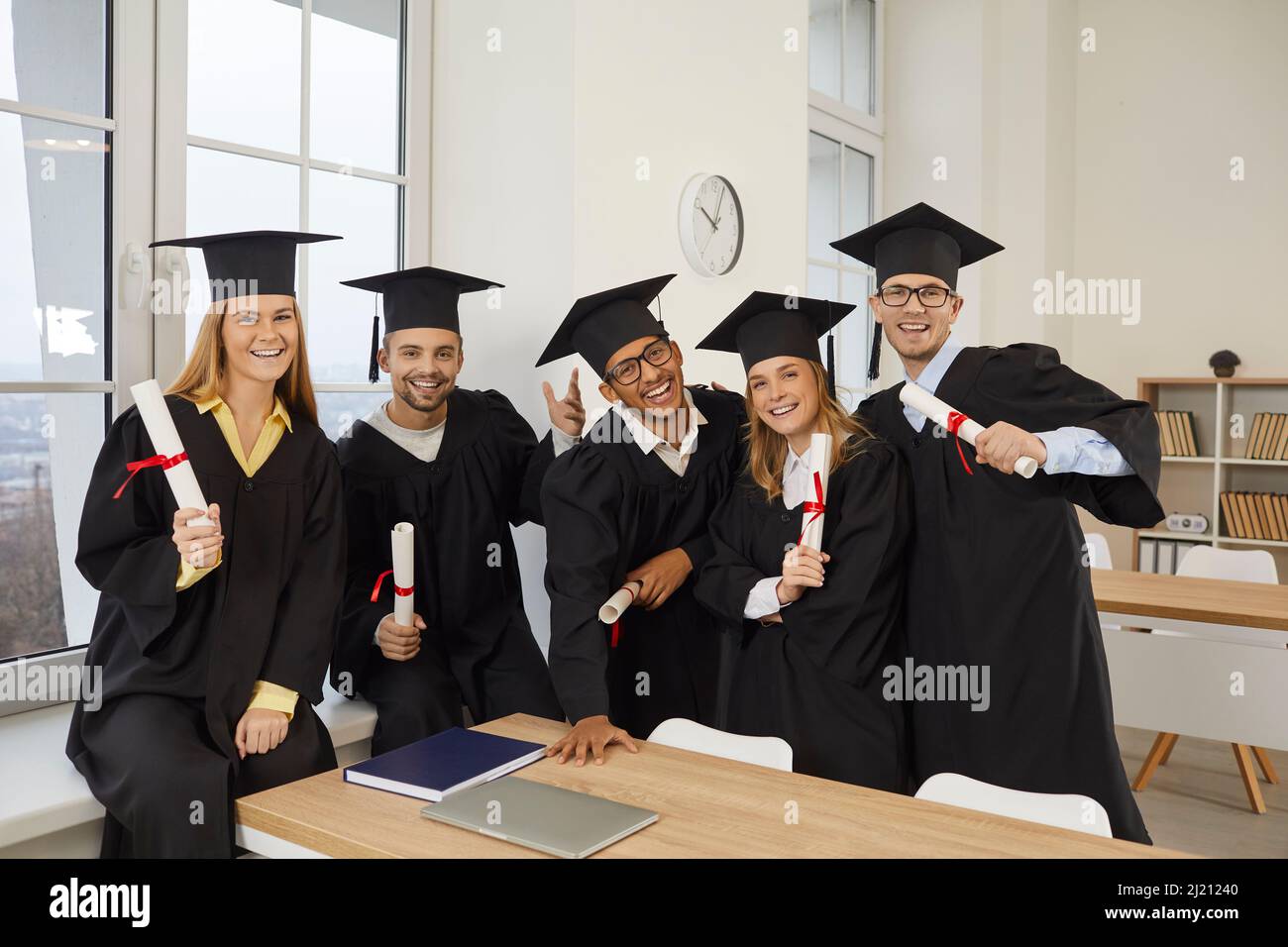 Happy, cheerful university graduates in caps and gowns celebrating ...