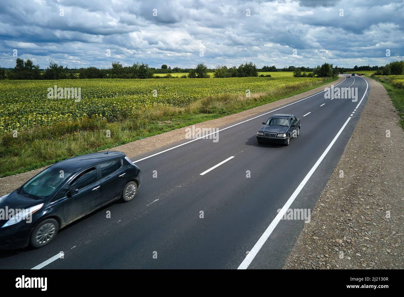 Aerial view of intercity road between green agricultural fields with ...