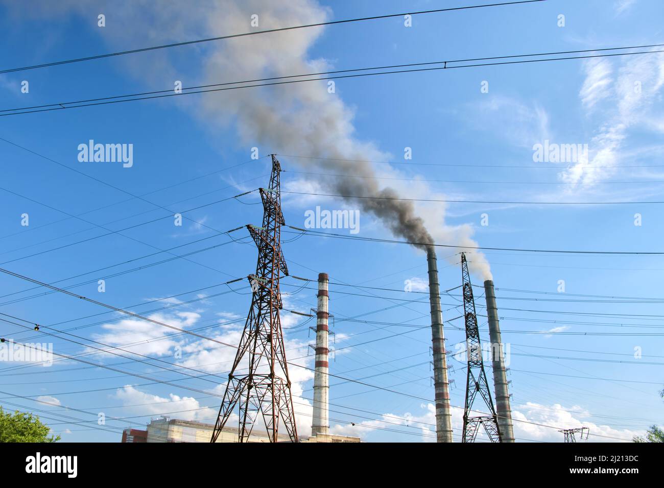 High voltage electric pylons against coal power plant high pipes with ...