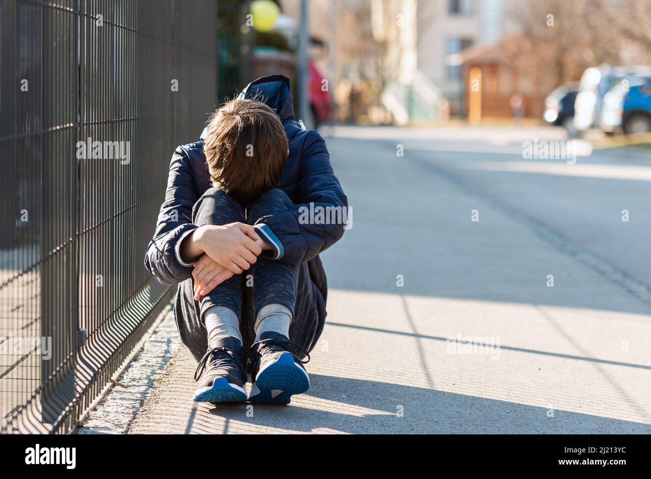 Sad boy sitting and crying on street. Negative emotion Stock Photo - Alamy
