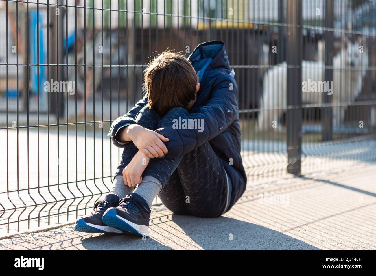 Sad boy sitting and crying on street. Negative emotion Stock Photo - Alamy