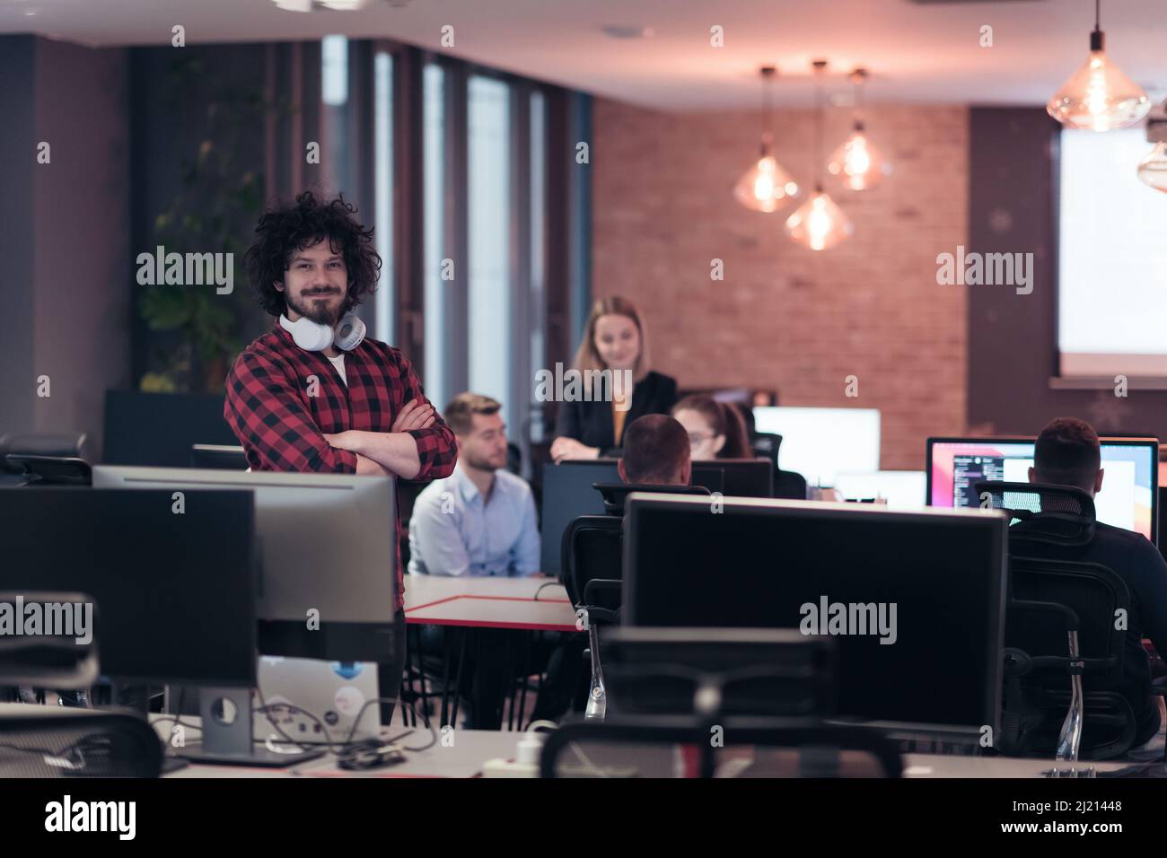 A young man with an Afro haircut stands in a modern office surrounded ...