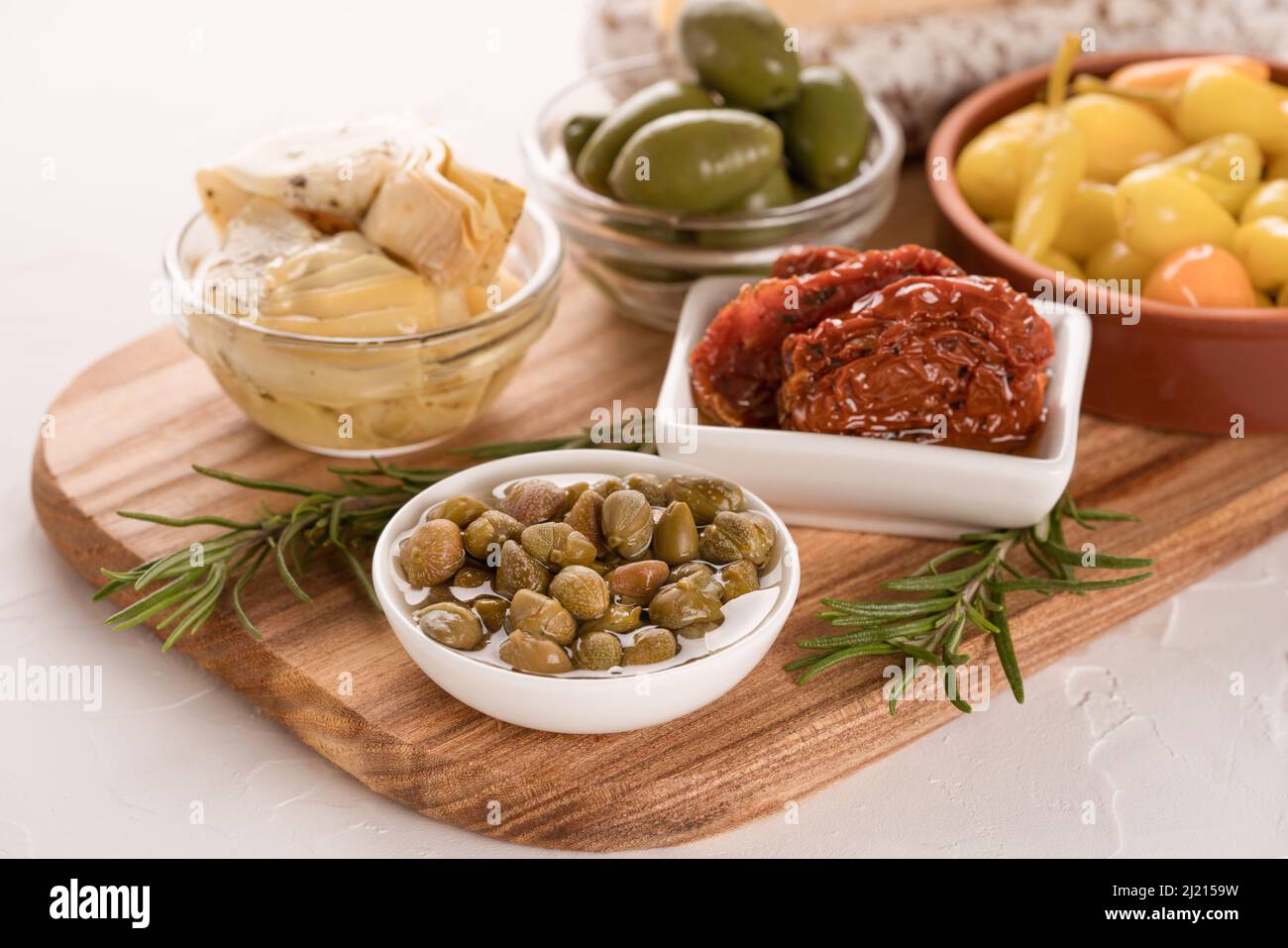Wooden board with selection of antipasti served on white table ...