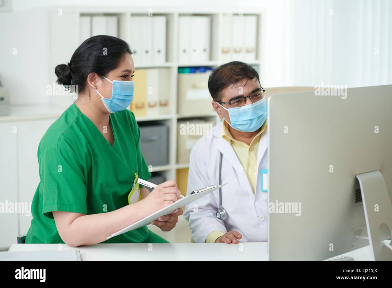 Medical workers in protective masks filling data in document when ...