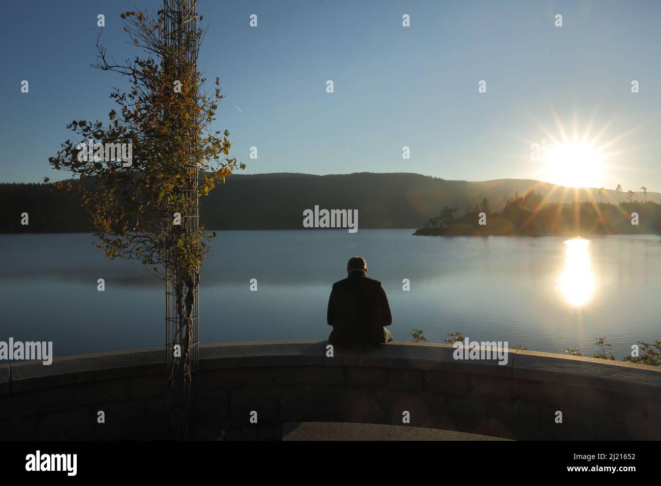 Sunset with a seated person from behind at the Schluchsee Stock Photo ...