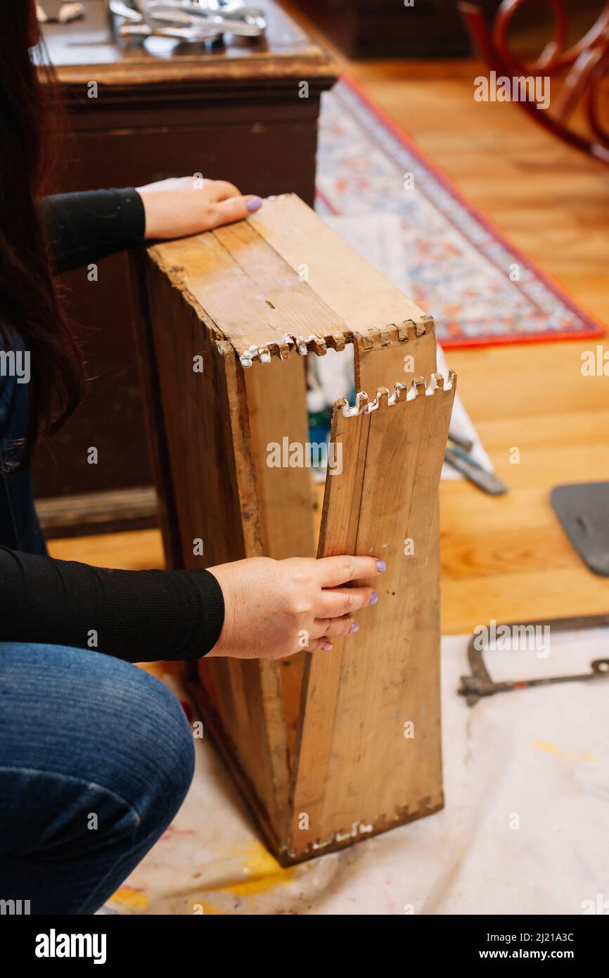 Caucasian Woman fixing wooden old box by putting it together in home ...