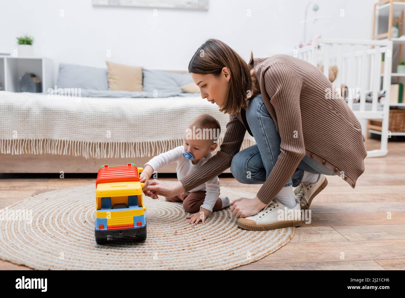 Mother and baby son playing with toy car in bedroom Stock Photo - Alamy