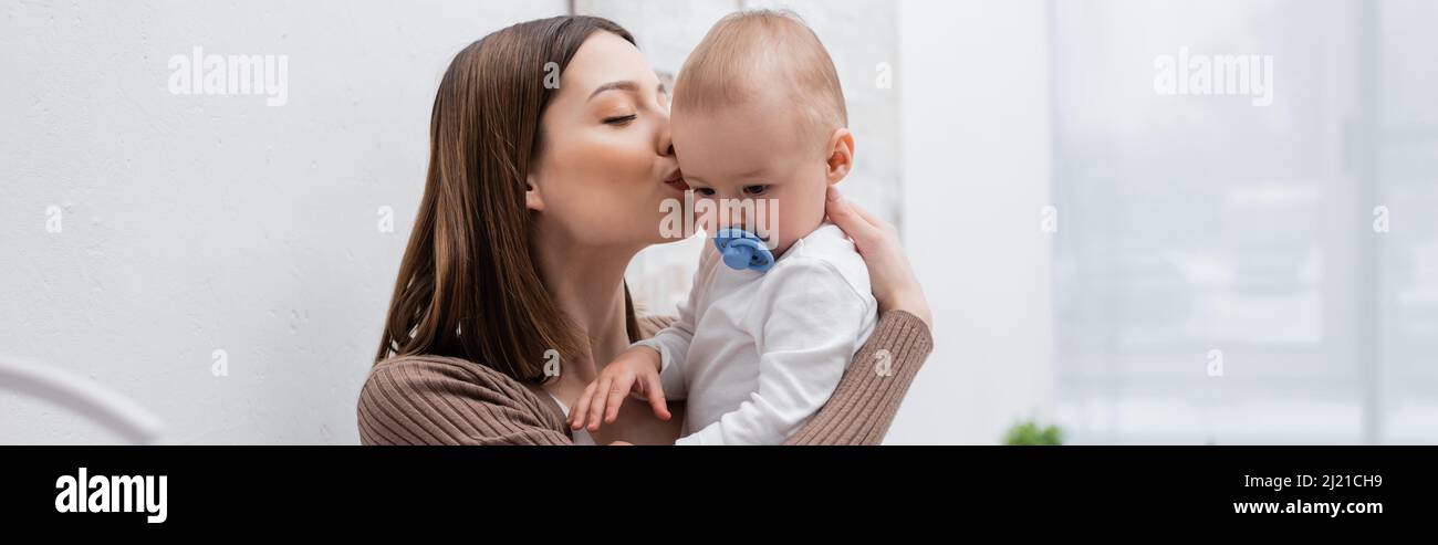 Woman kissing baby son with pacifier at home, banner Stock Photo - Alamy