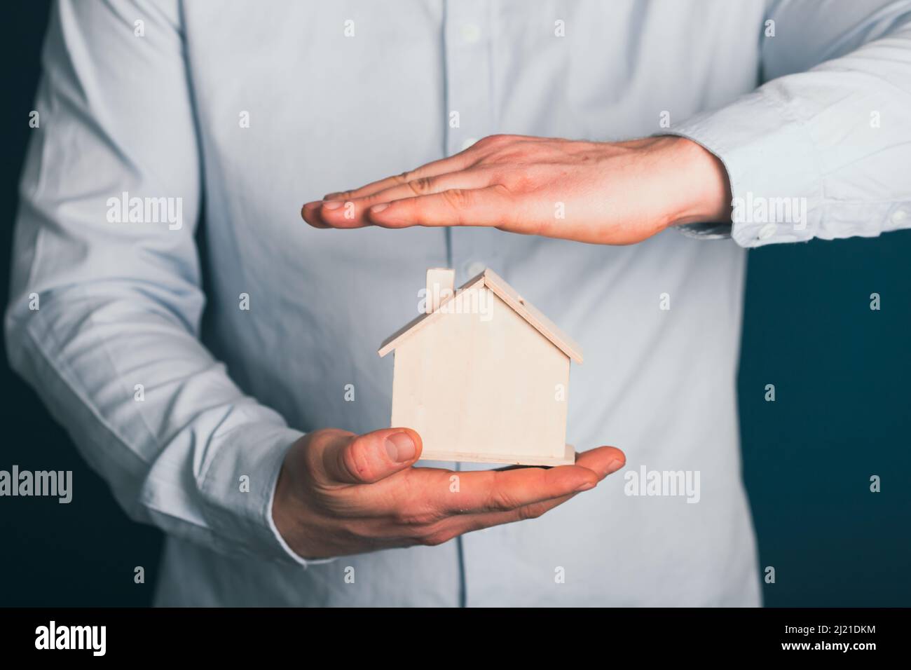 Real estate agent protecting house model. Property insurance and ...