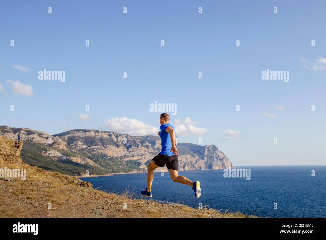 male athlete running uphill trail on sky and sea background Stock Photo ...