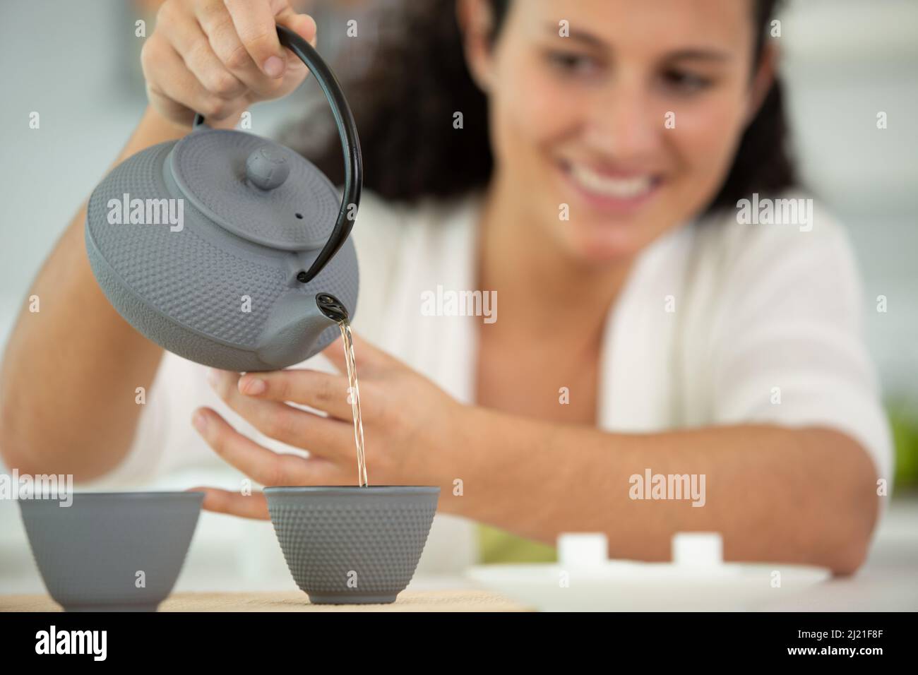 smiley girl pouring from teapot Stock Photo - Alamy