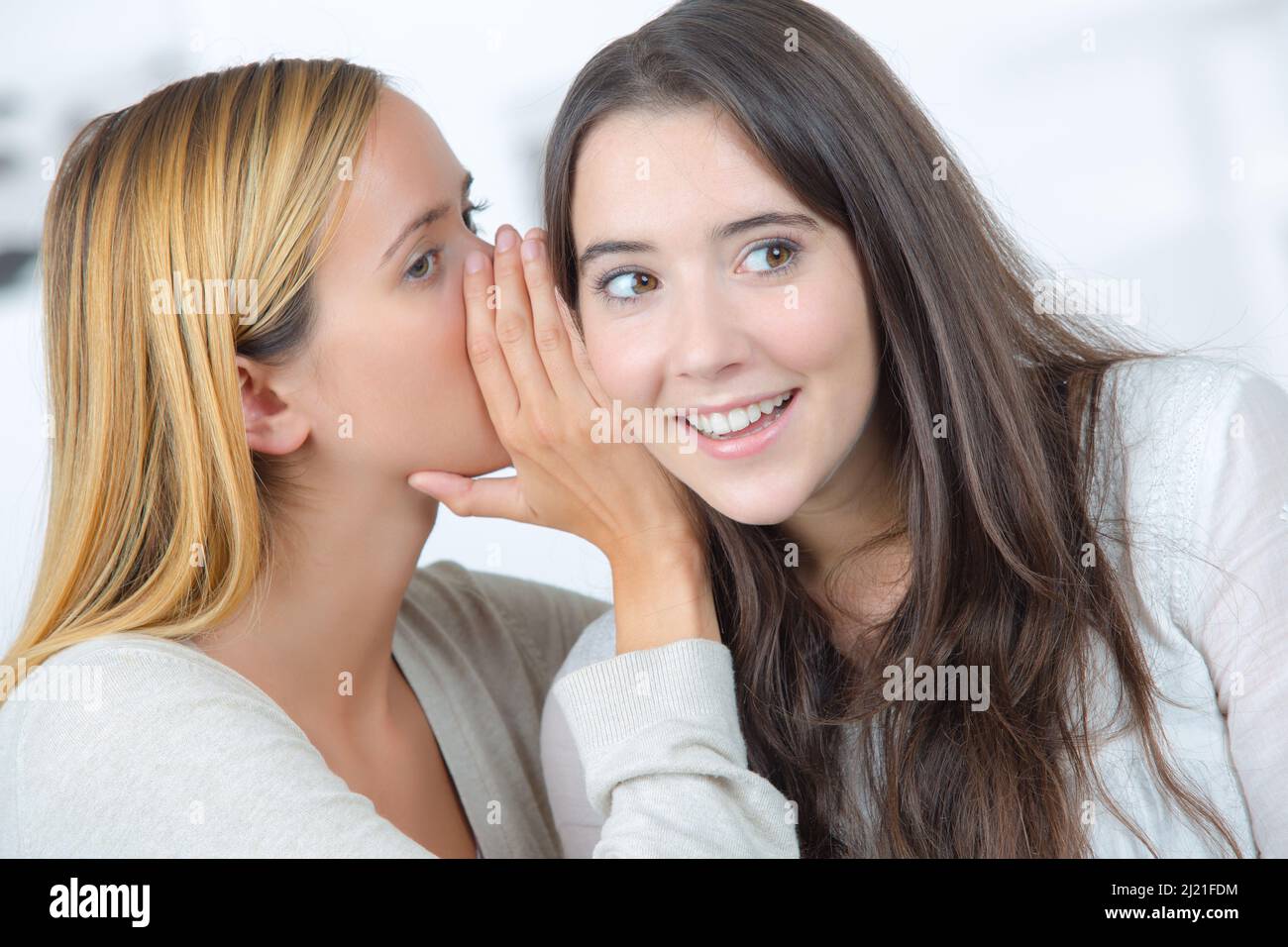 one friend is whispering a secret to the other Stock Photo - Alamy