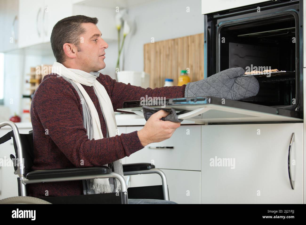 disabled man taking food from the oven Stock Photo - Alamy