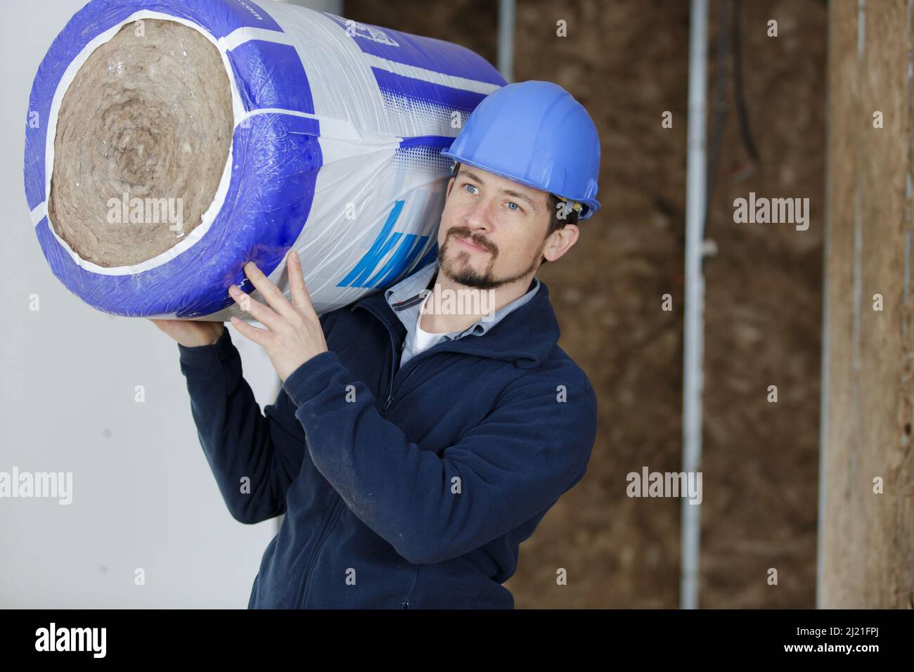 young male worker carrying a roll of insulation Stock Photo - Alamy