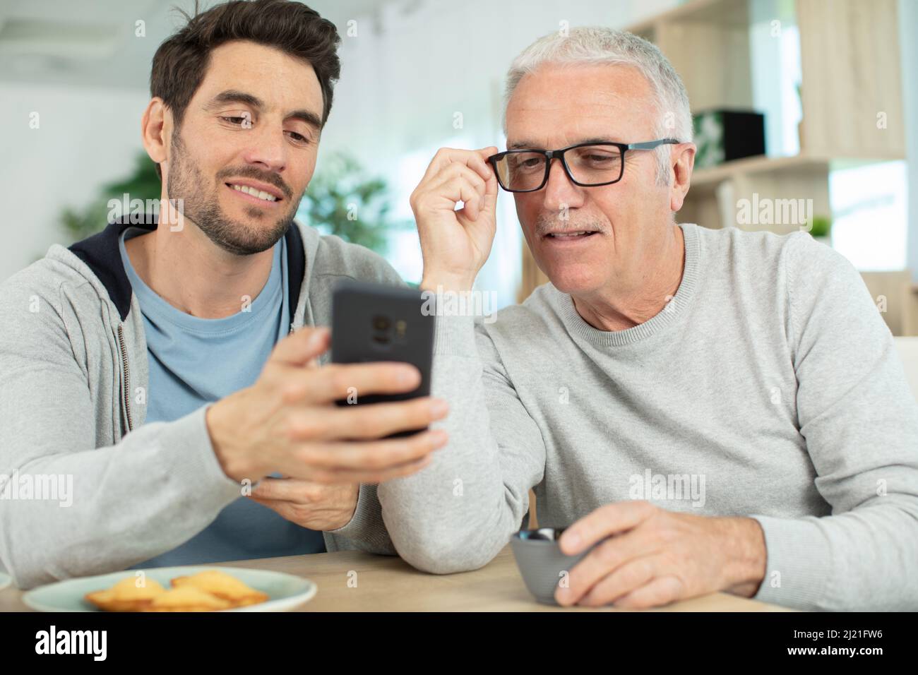 senior dad and son checking mobile phone Stock Photo - Alamy