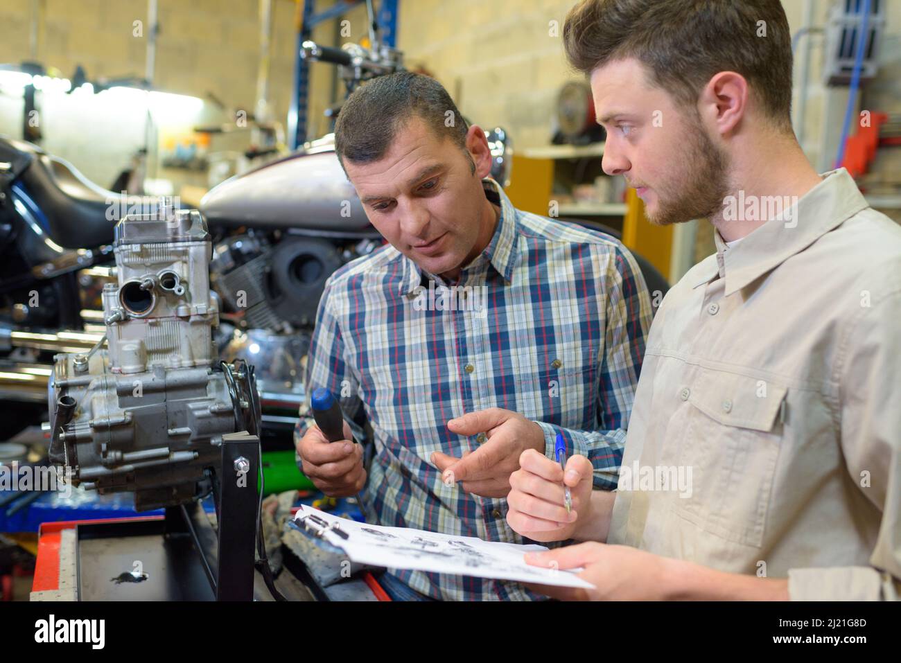 senior and junior mechanics in motorcycle garage Stock Photo - Alamy