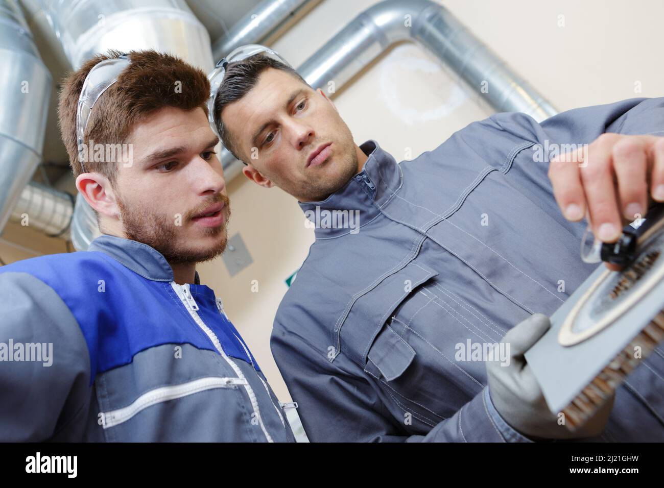 skilled worker giving instructions to an apprentice in a factory Stock ...