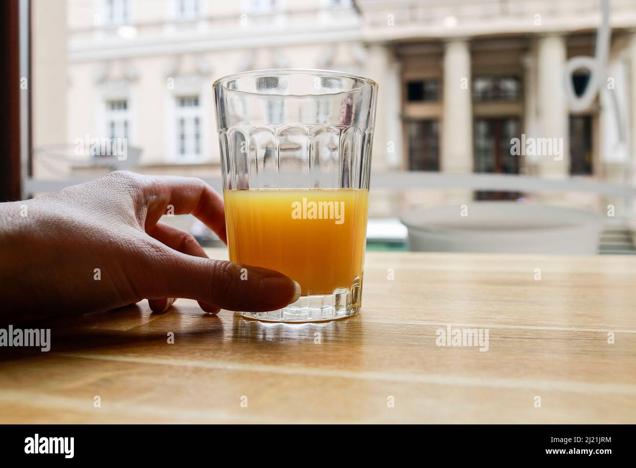Half full or half empty glass of orange juice by the window. Blurred ...