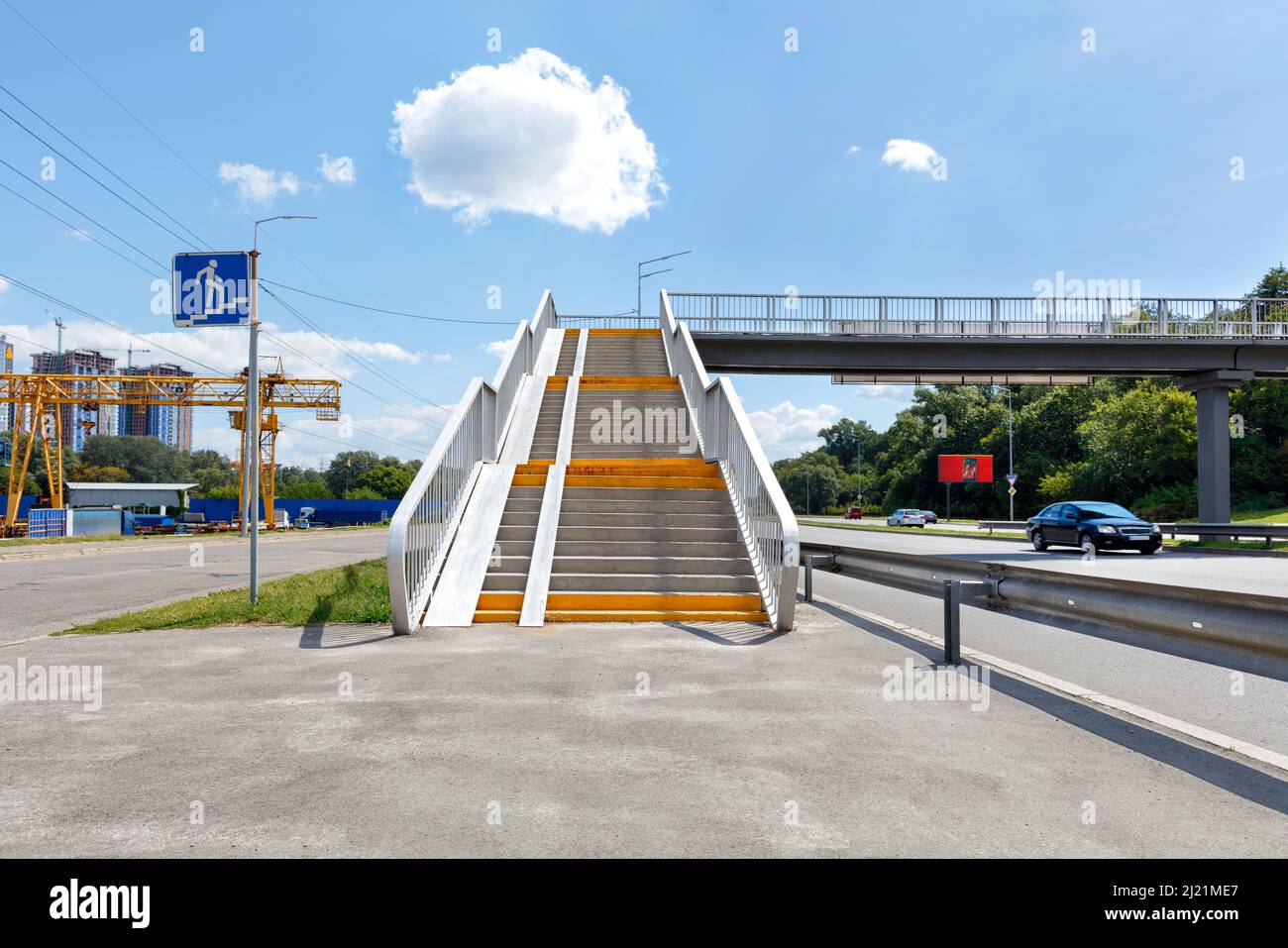 A pedestrian overpass across a busy city highway provides access from a ...