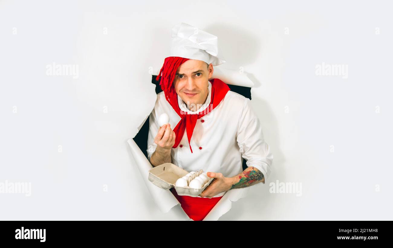 A handsome man with red dreadlocks holds it in his hand chicken eggs ...