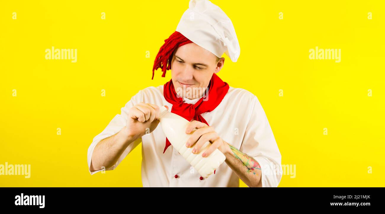 Man with red dreadlocks with bottle milk. Confident young cook in white ...