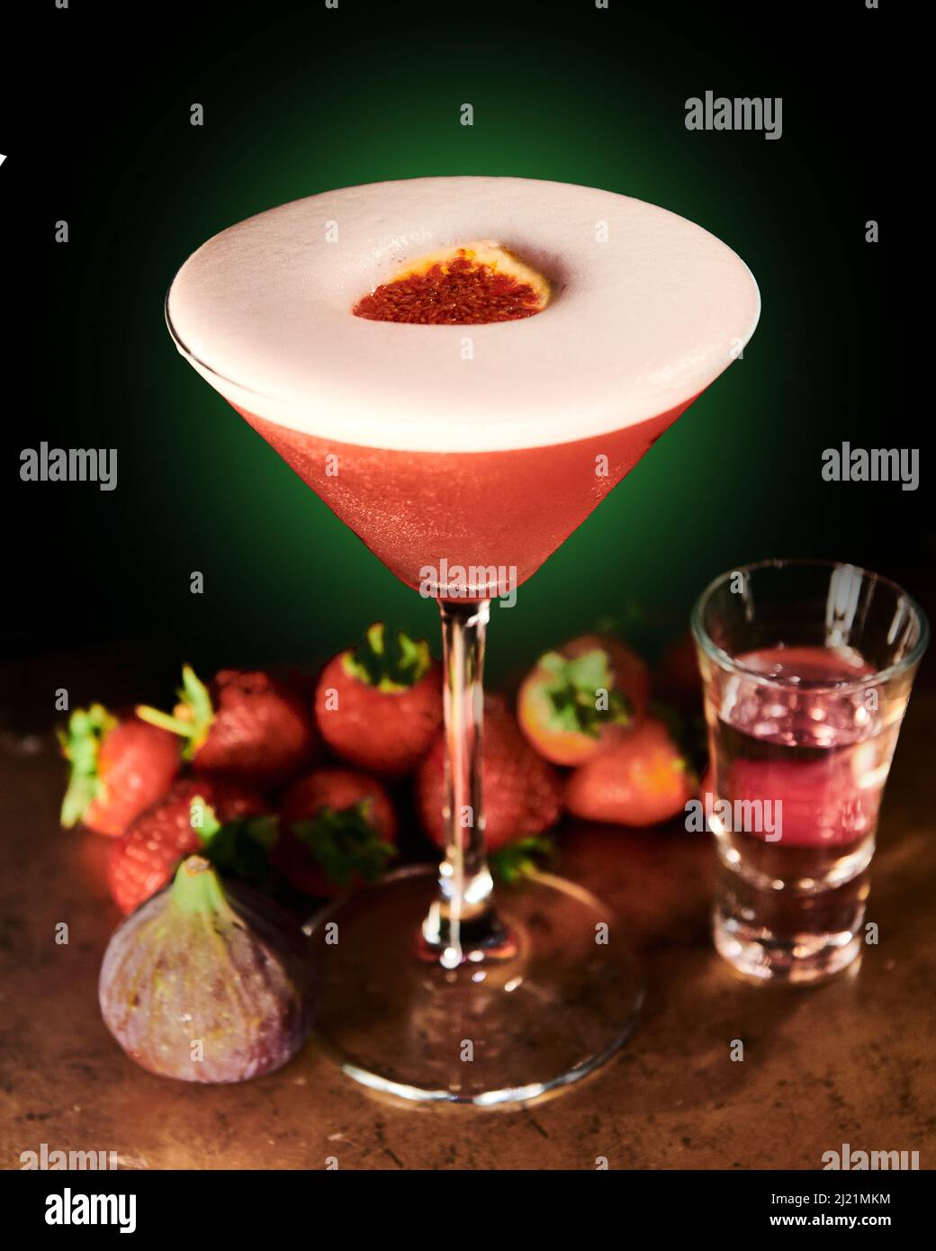 A red foamy fig and strawberry inspired cocktail in a martini glass ...