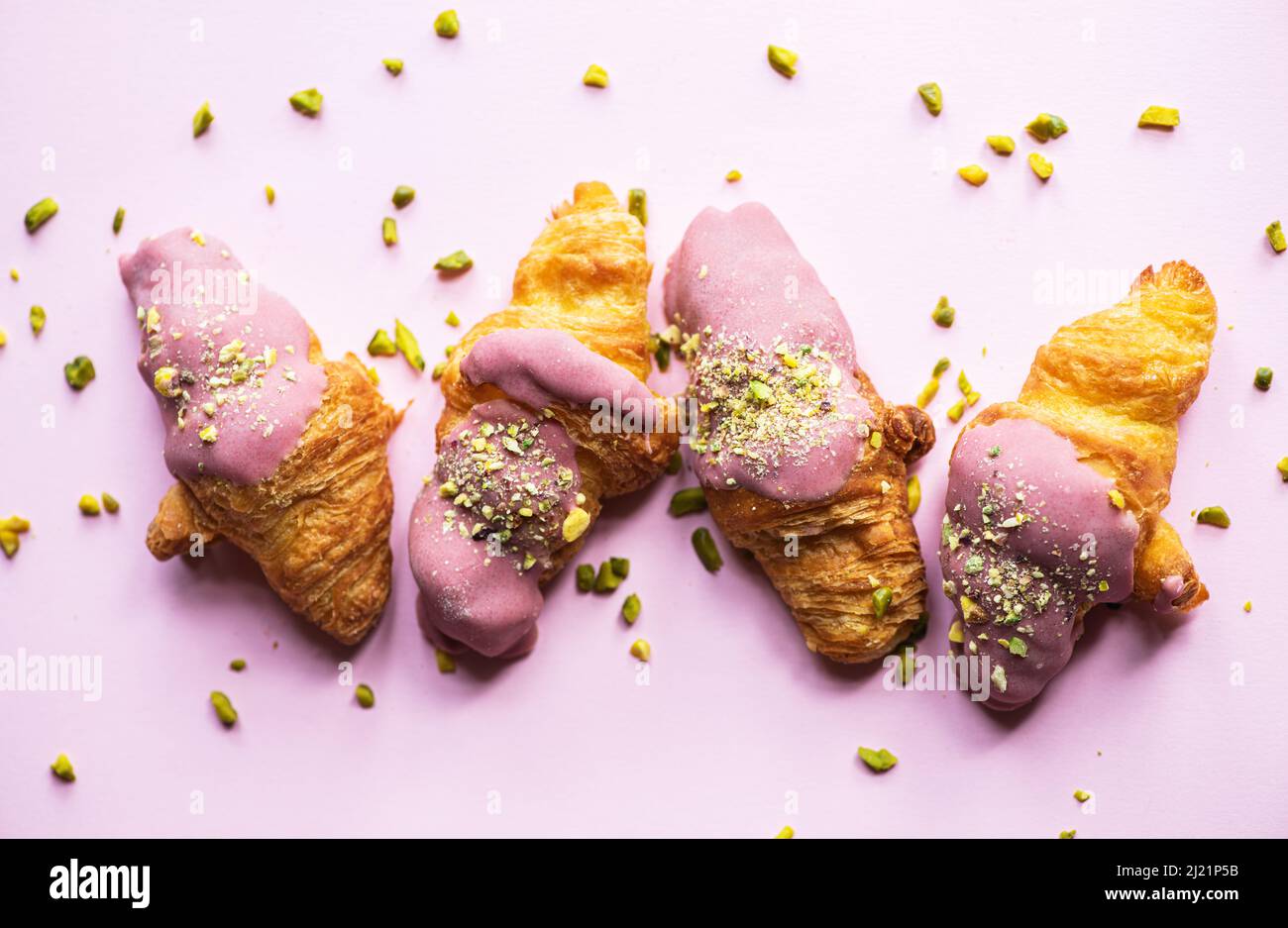 Mini-croissants with ruby chocolate and pistachios on a pink background ...