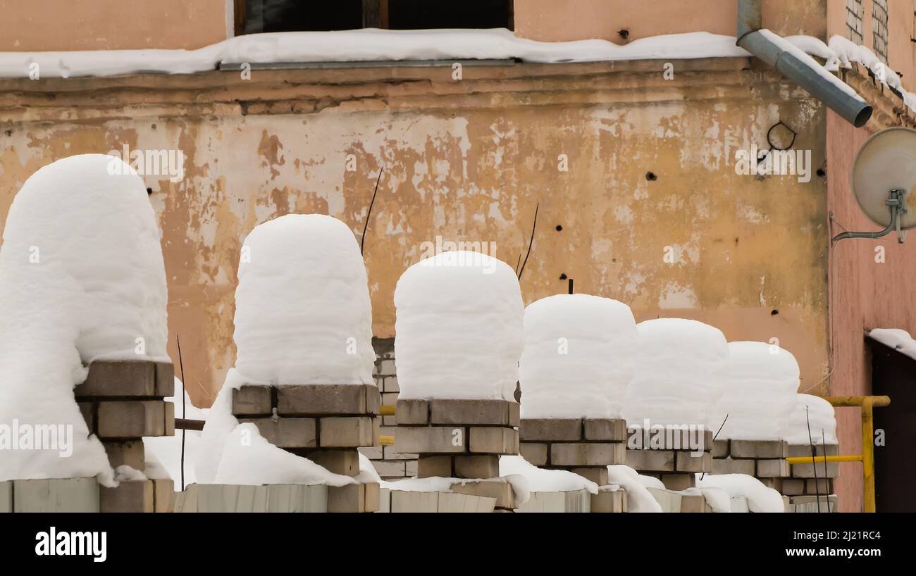 Tall beautiful columns of snow on brick pillars. An even row of small ...
