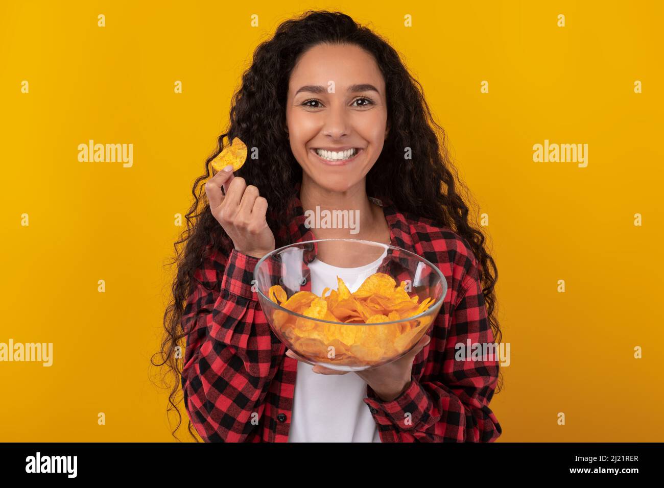 Excited Latin Lady Eating Delicious Potato Crisps Stock Photo - Alamy