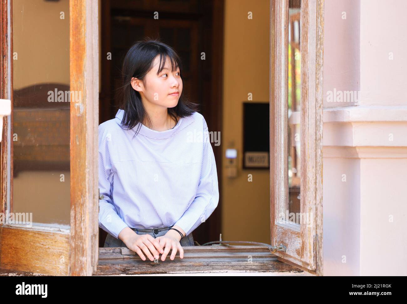 young college female girl student look out through window in old ...