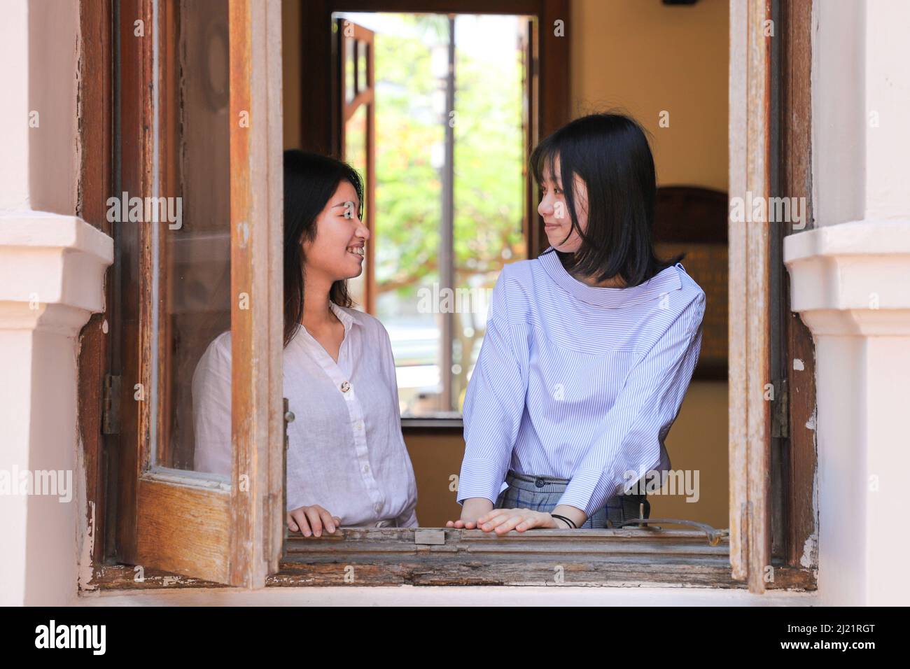 young college female girl student chat while leaning at window in old ...