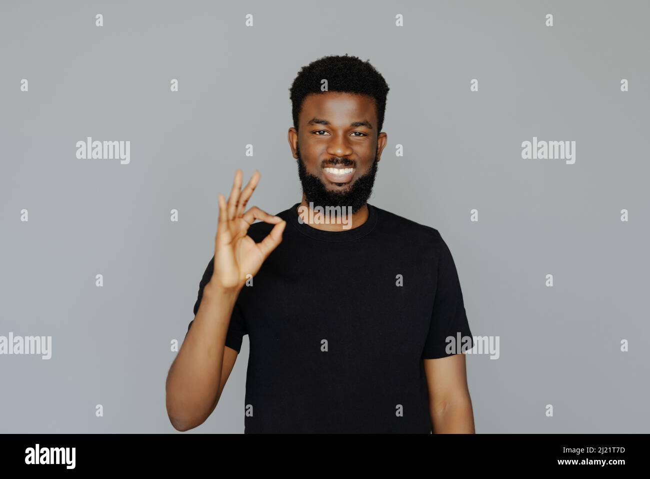 Young black man having happy look, smiling, gesturing, showing OK sign ...