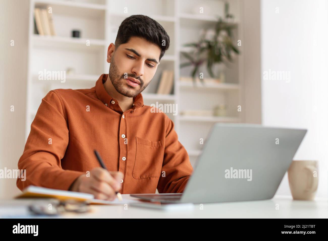 Portrait of focused Arab man using pc and writing Stock Photo - Alamy