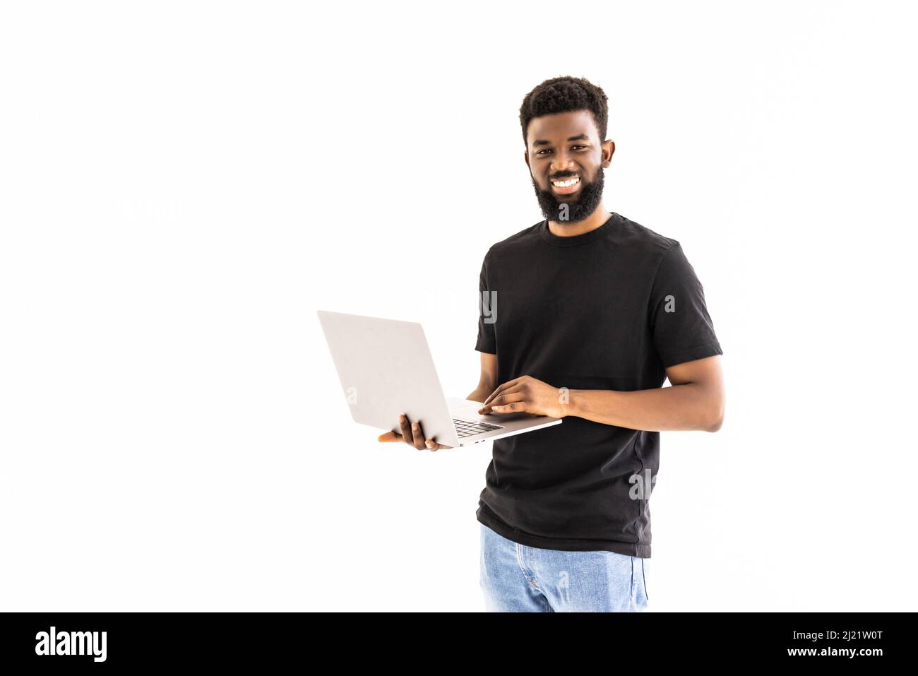 Young smiling african man standing and using laptop computer isolated ...