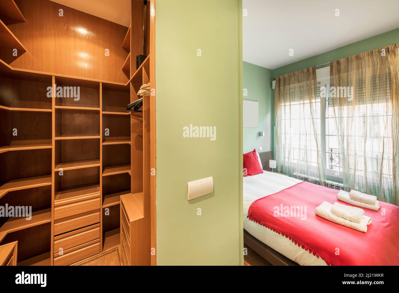 Bedroom with walk-in closet with wooden shelves and chest of drawers in ...