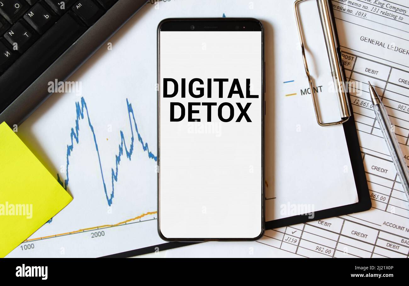 Hands holding a mobile phone with Digital Detoxing text on the screen ...