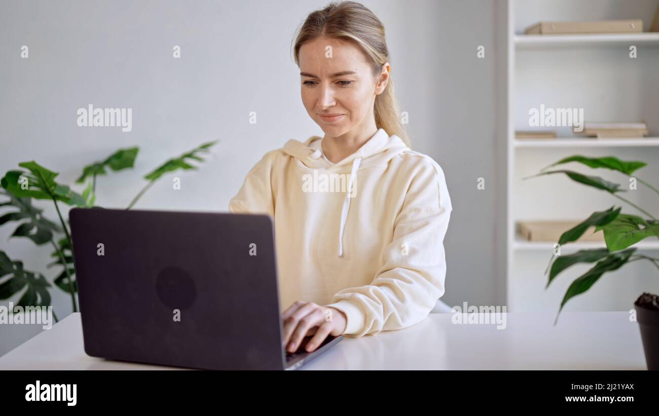 A closeup shot of a Caucasian woman working with her computer at home ...