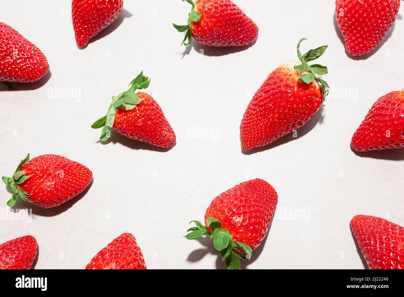 Fresh, ripe strawberries brightly illuminated form a pattern on white ...