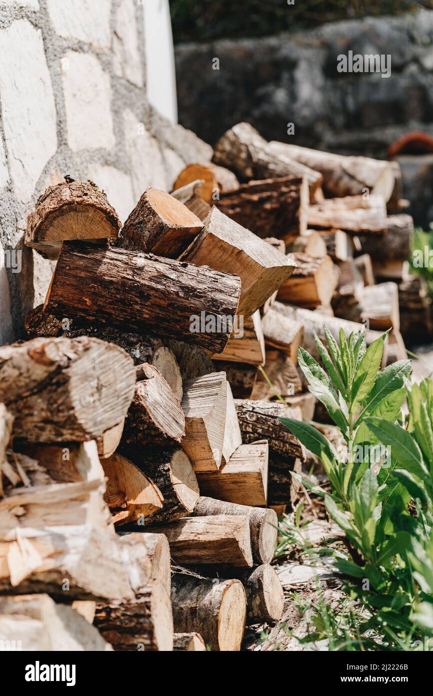 Wood folded in a row near a stone wall and grass Stock Photo - Alamy