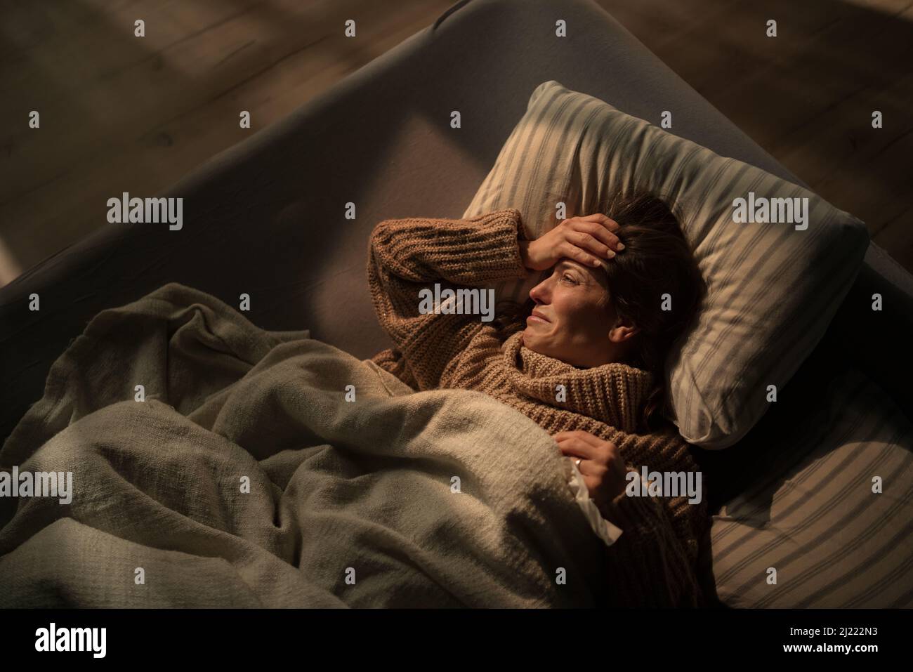 Sad woman suffering from covid depression lying in bed in night Stock ...