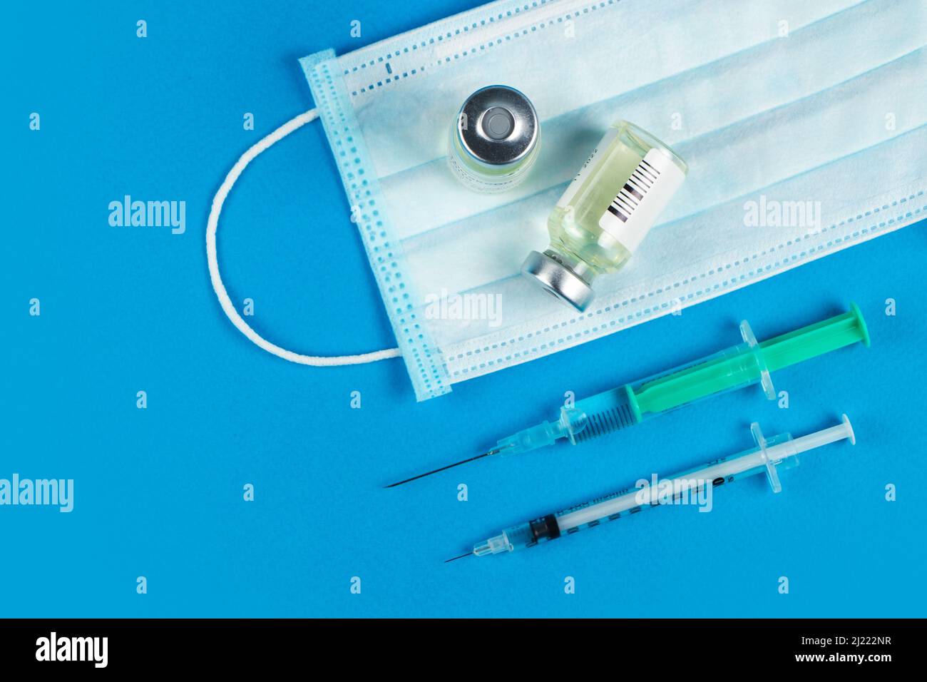 Medical bottle, vials, syringes and face mask on blue background with ...