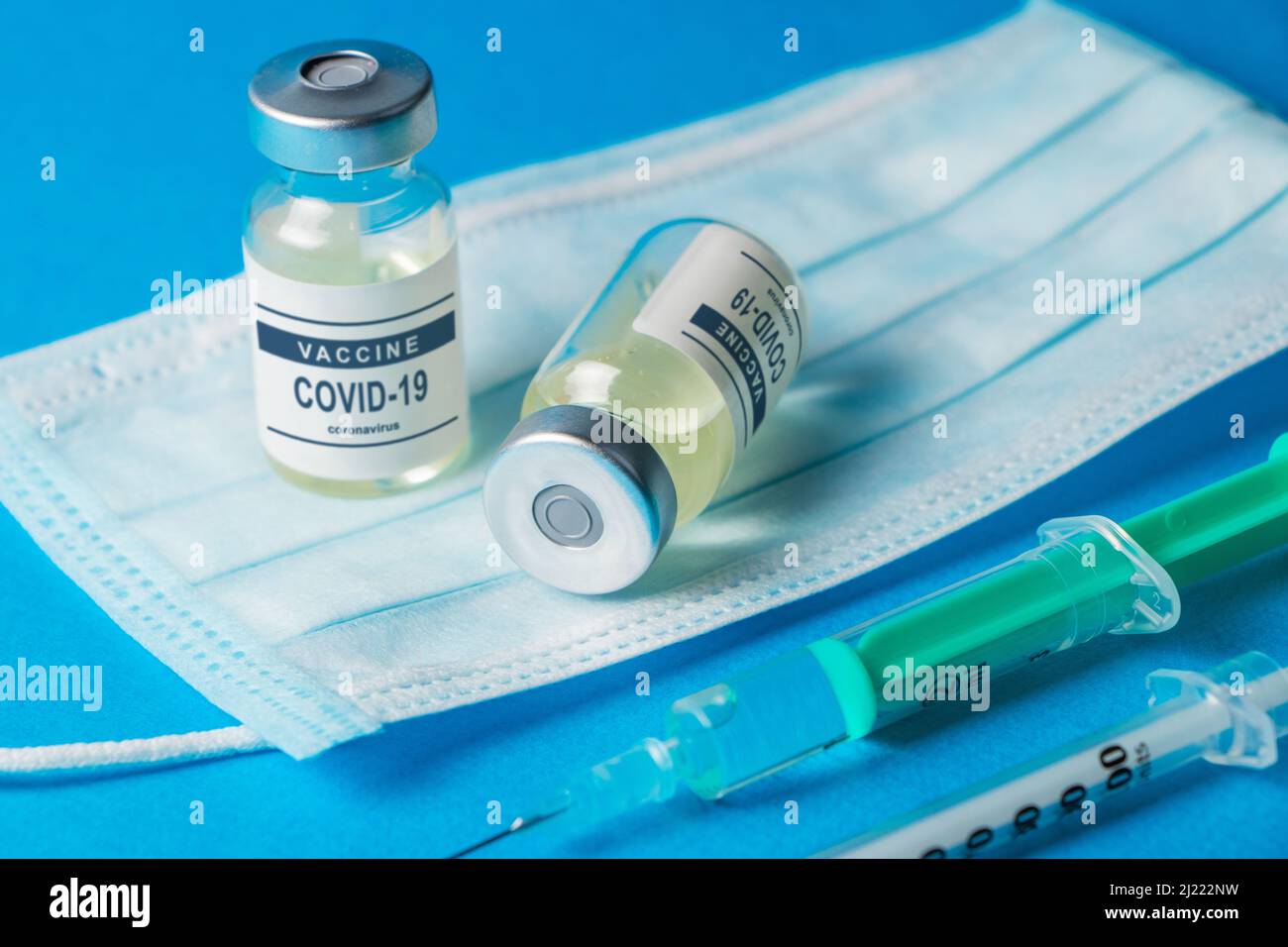 Medical bottle, vials, syringes and face mask on blue background with ...