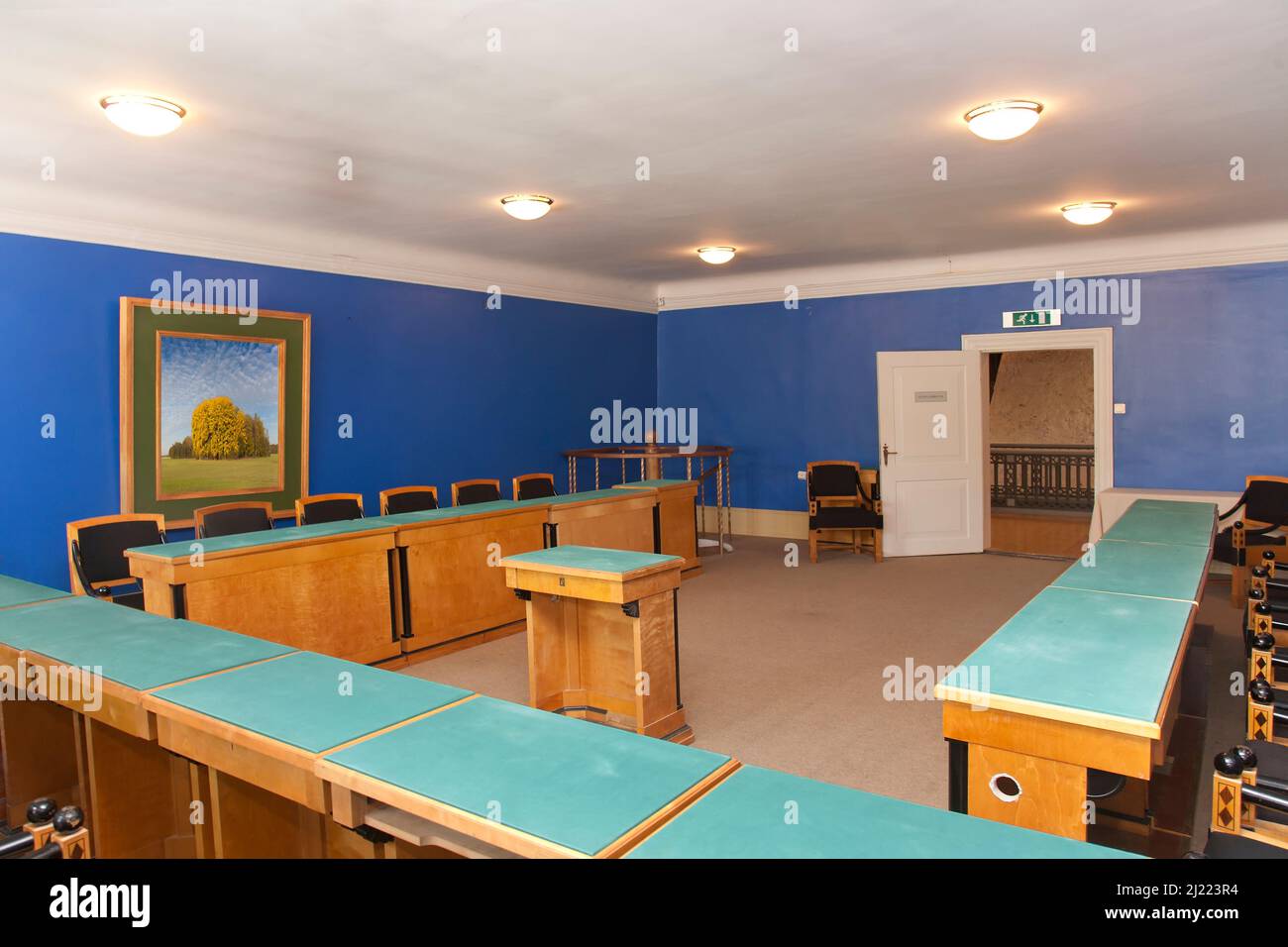 A large meeting room, with desks and chair and central podium, old ...