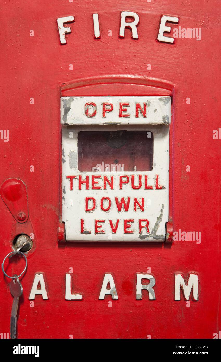A red metal historic antique fire alarm box. An alarm lever with ...